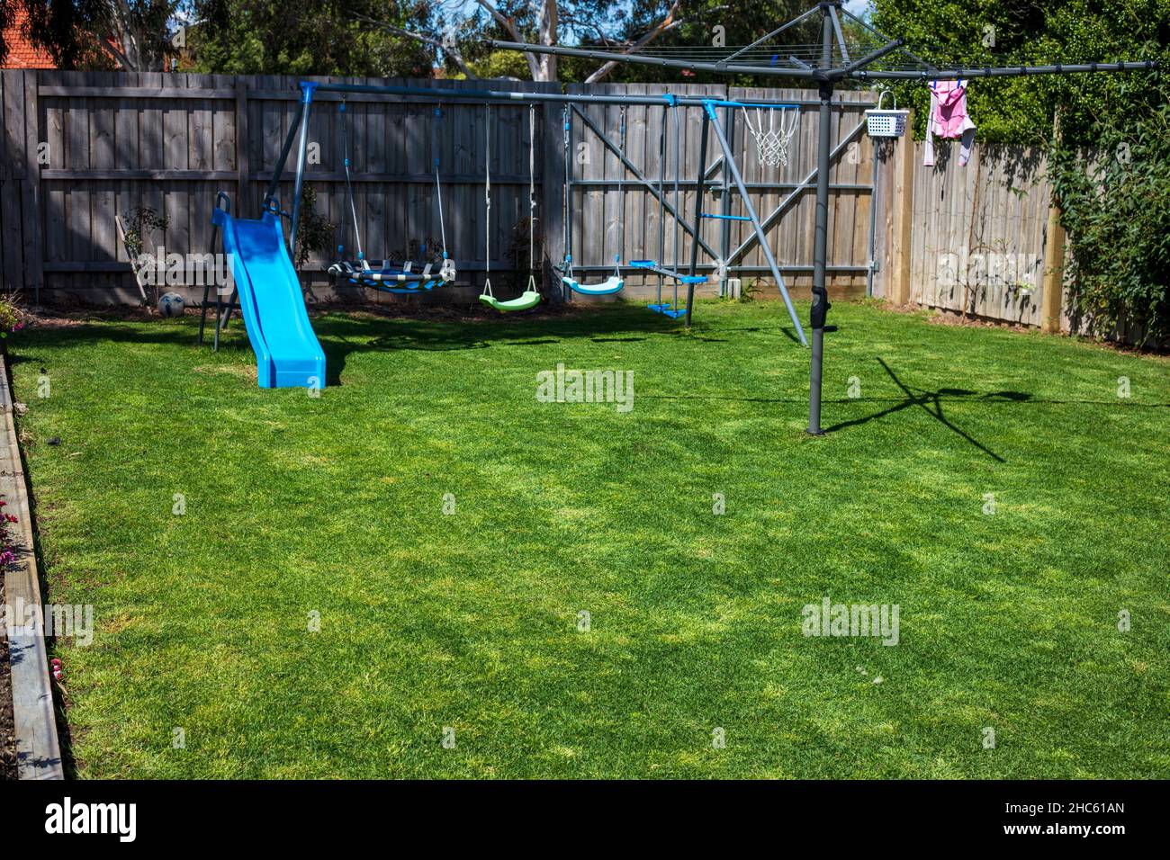 Bright summer day outdoors in a backyard with a swing set next to a ...