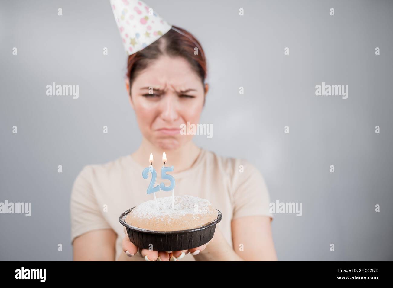 The unhappy woman is holding a cake with candles for her 25th birthday ...