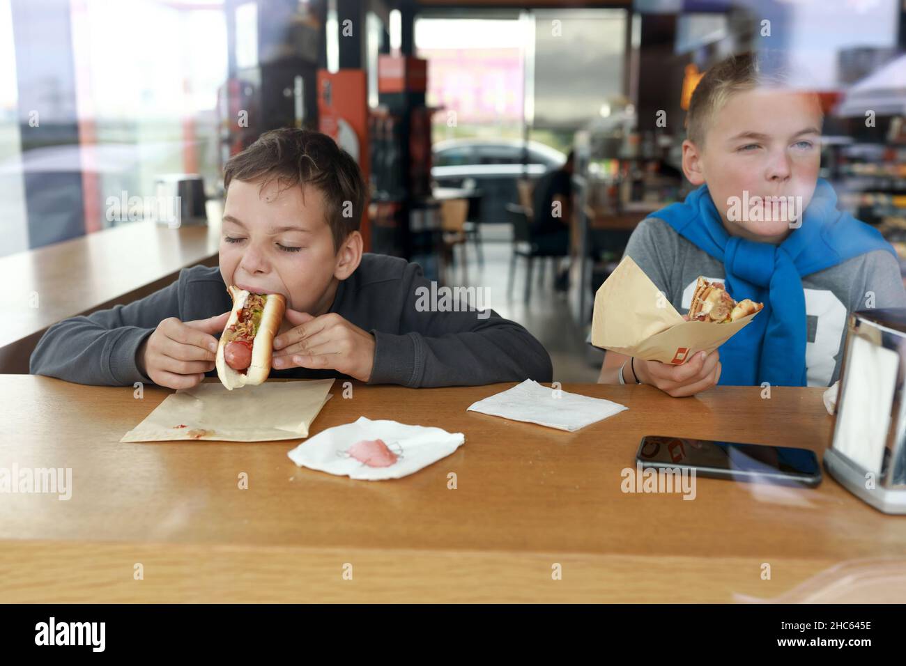 Portrait of two children eating Hot Dog in restaurant Stock Photo - Alamy