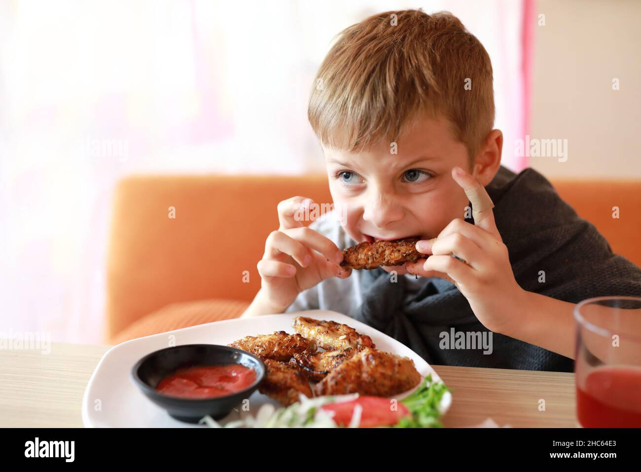 Child eating roasted chicken wings in restaurant Stock Photo - Alamy