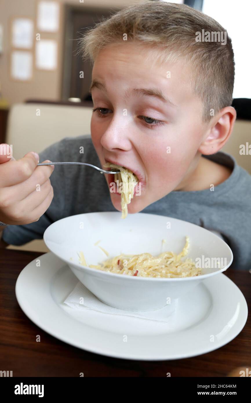 Boy eating pasta with cheese in restaurant Stock Photo - Alamy