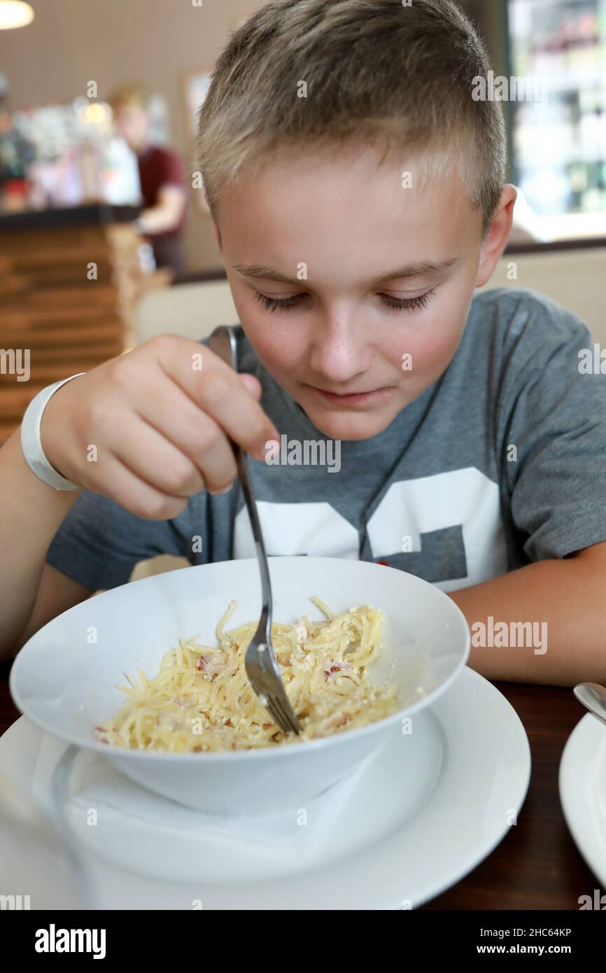 Child eating pasta with cheese in restaurant Stock Photo - Alamy