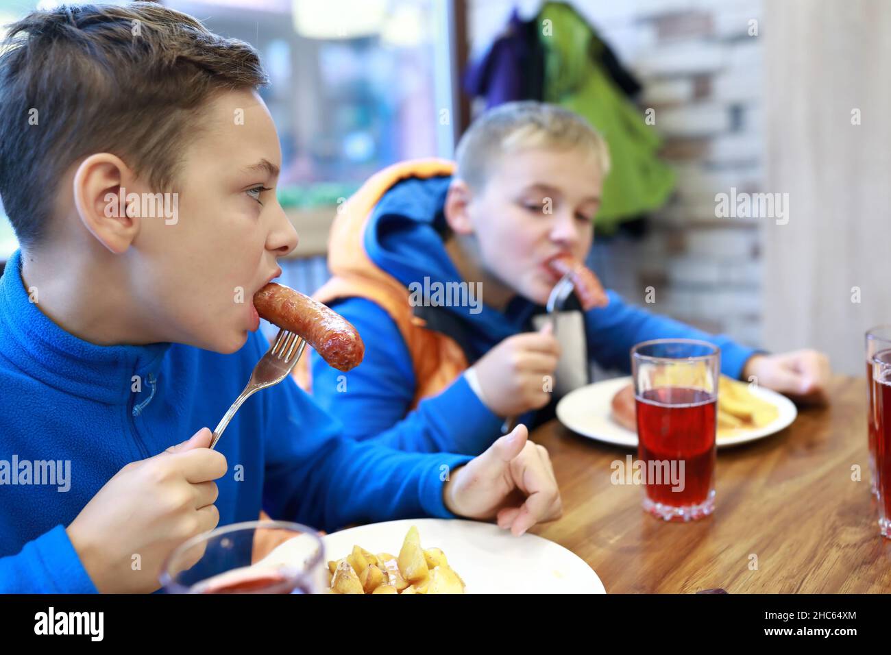 Two children eating sausages at table in restaurant Stock Photo - Alamy