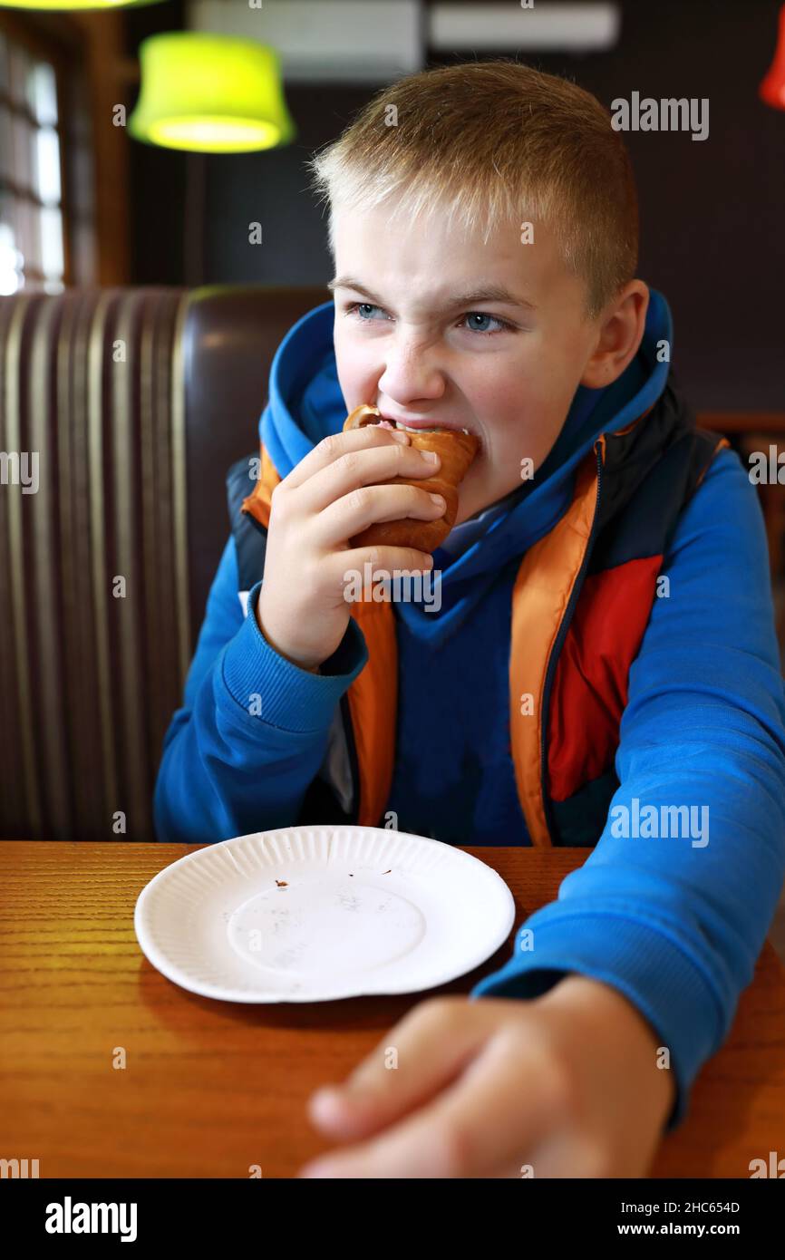 Child eating Hot Dog at table in restaurant Stock Photo - Alamy