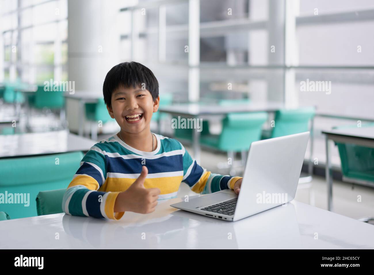 Portrait of Cute Asian boy studying or playing game with laptop ...