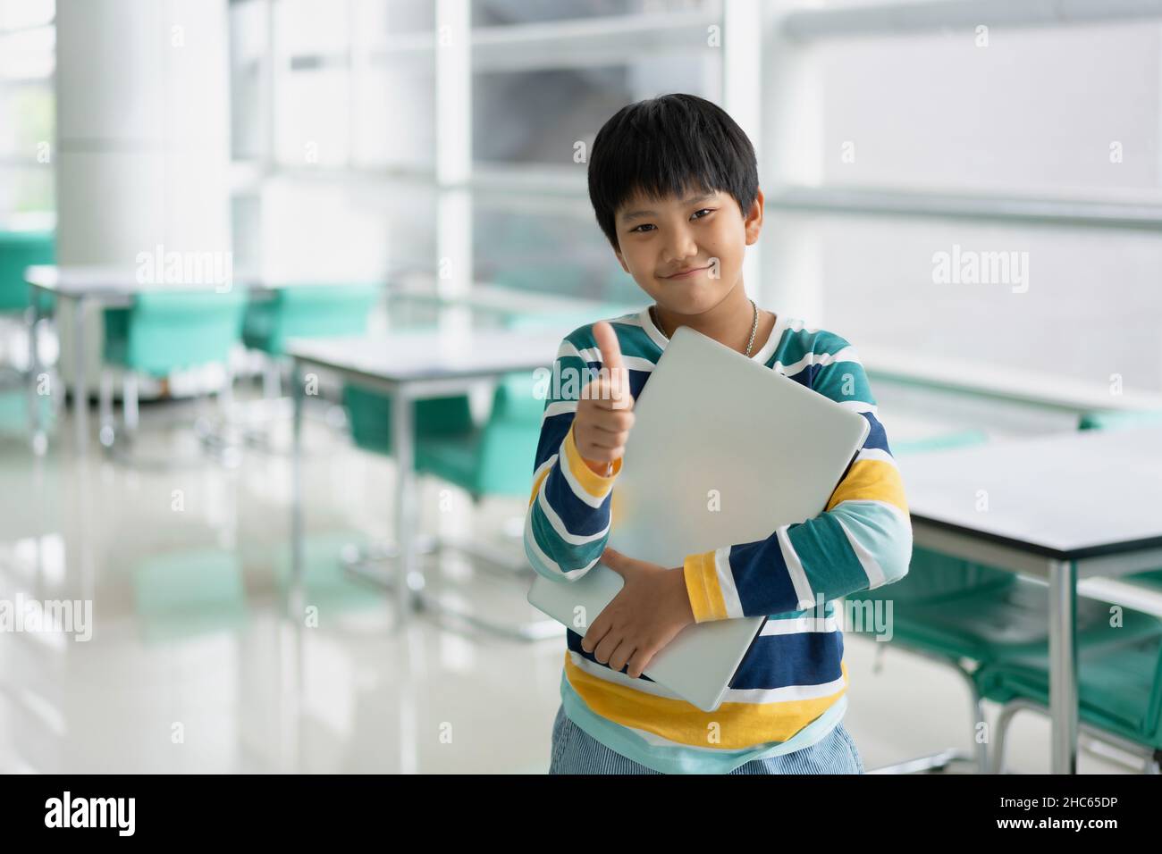 Portrait of Cute Asian boy studying or playing game with laptop ...