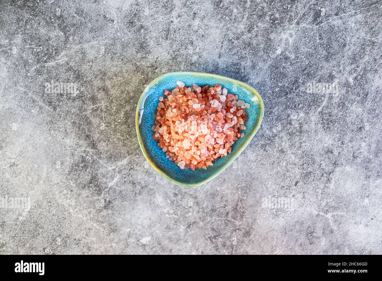 Pink Himalayan coarse rock salt on a little blue plate on gray ...