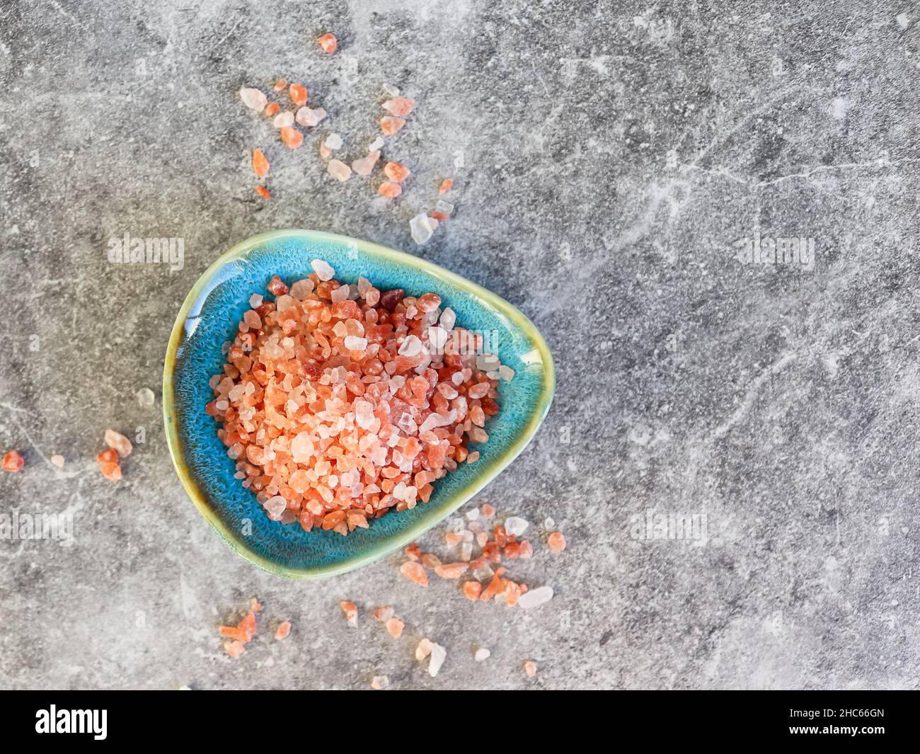 Pink Himalayan coarse rock salt on a little blue plate on gray ...