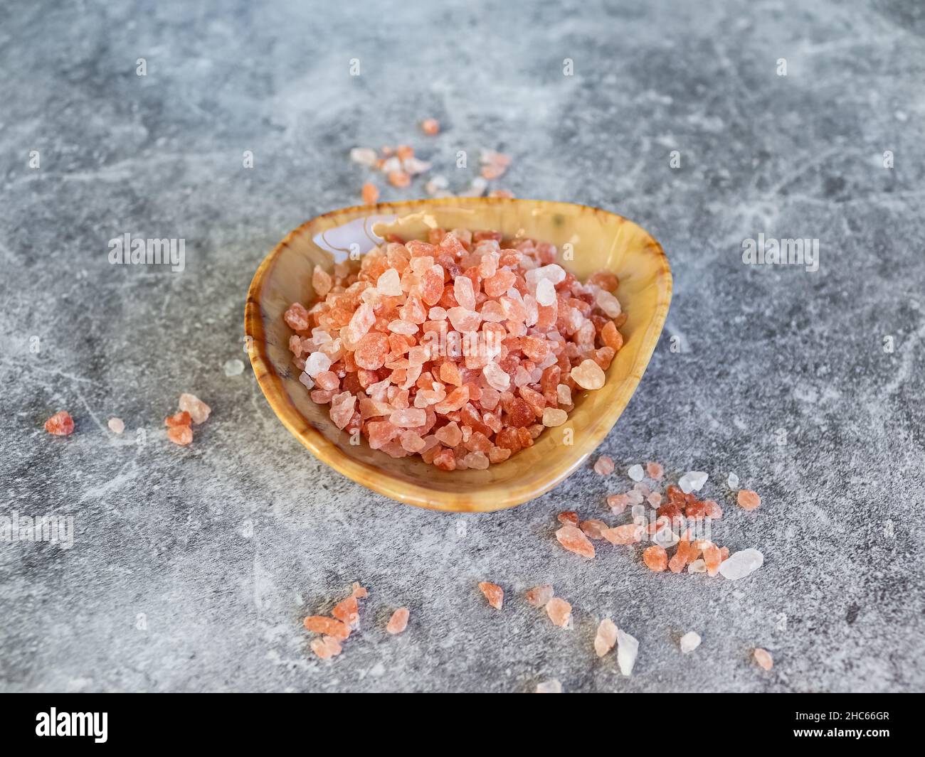 Pink Himalayan coarse rock salt on a little brown plate on gray ...