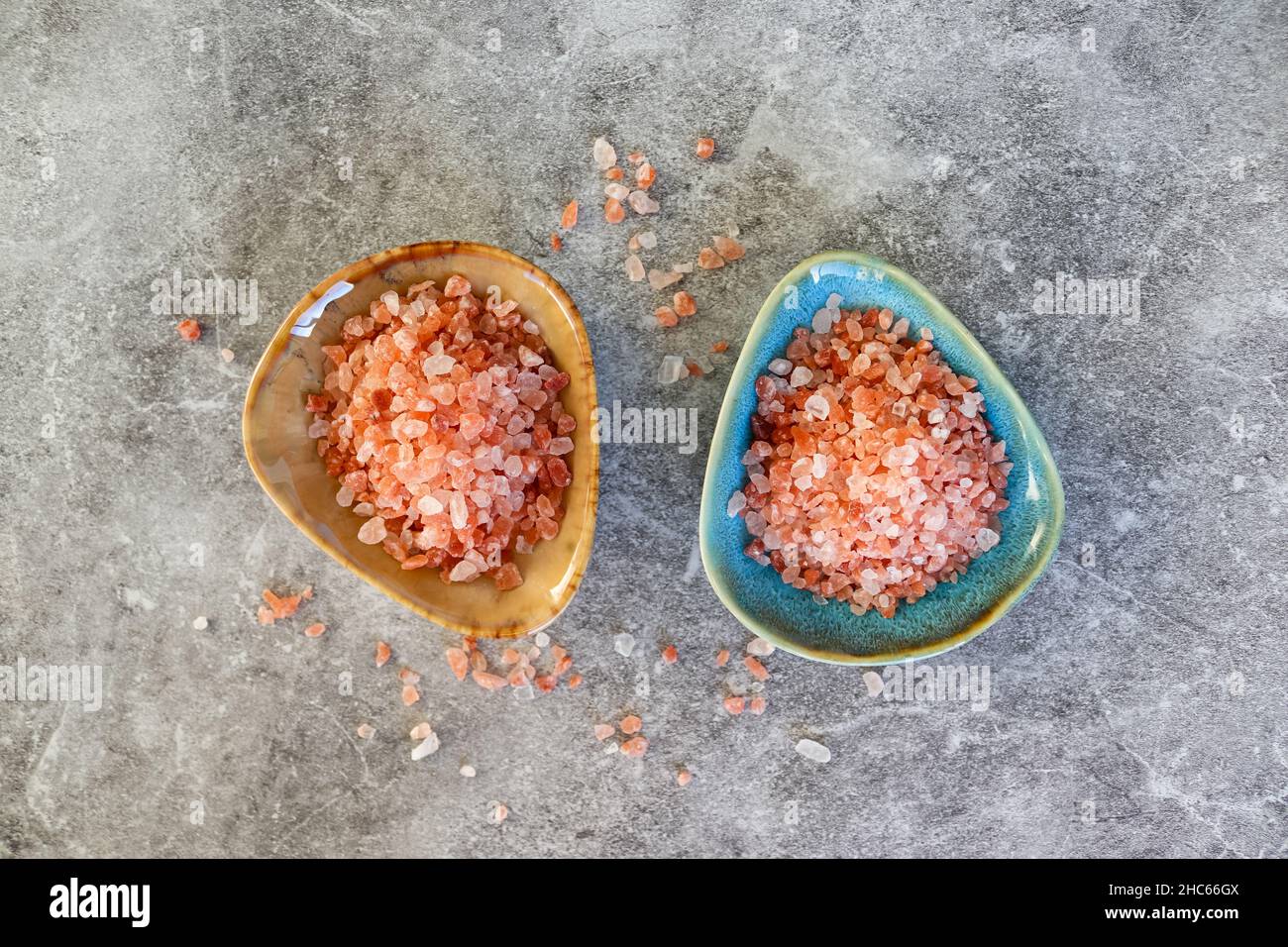 Pink Himalayan coarse rock salt i two small plates on gray background ...