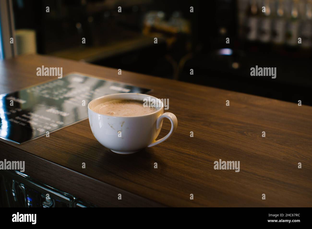 Dirty white coffee cup stands on the wooden counter of a coffee shop ...