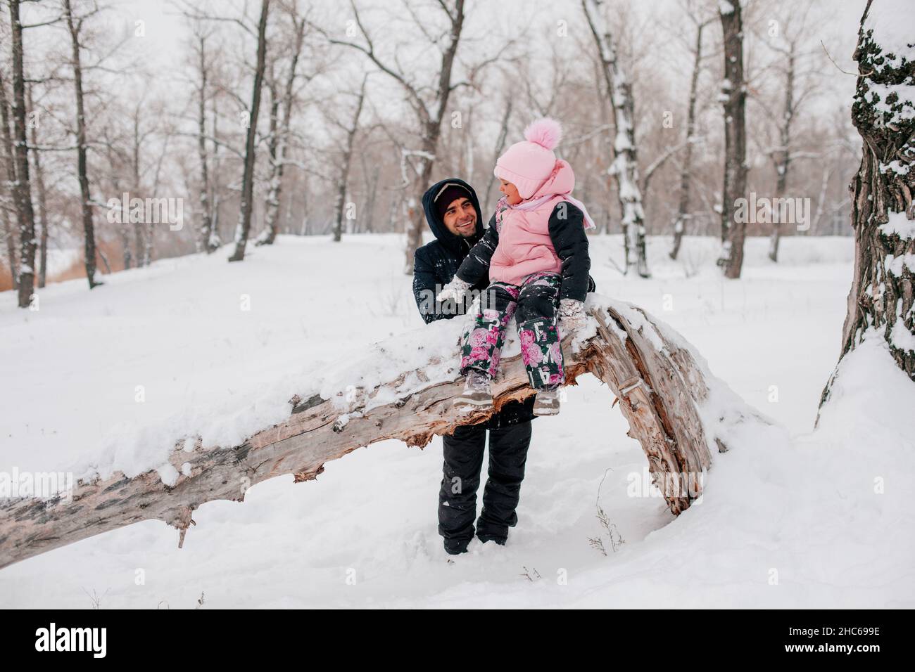 Distant photo of female kid sitting on tree log wearing pink winter ...