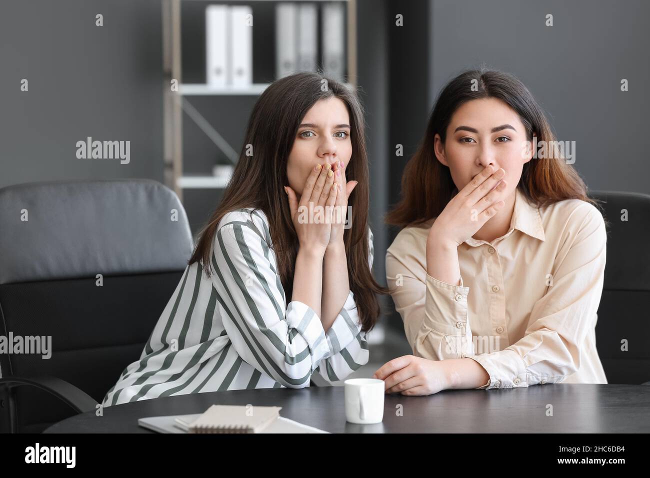 Female colleagues gossiping in office Stock Photo - Alamy