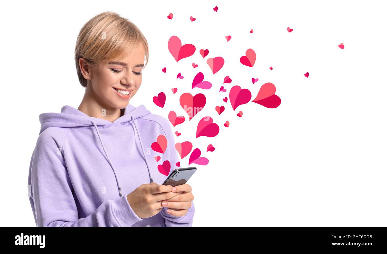 Beautiful young woman with phone sending love message on white ...