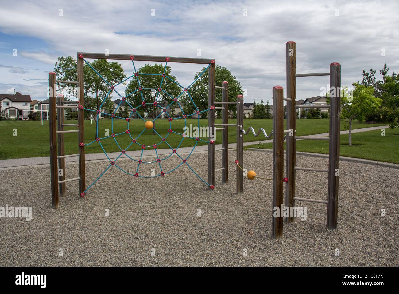 Spider web rope climber in an outdoor playground against a cloudy sky ...