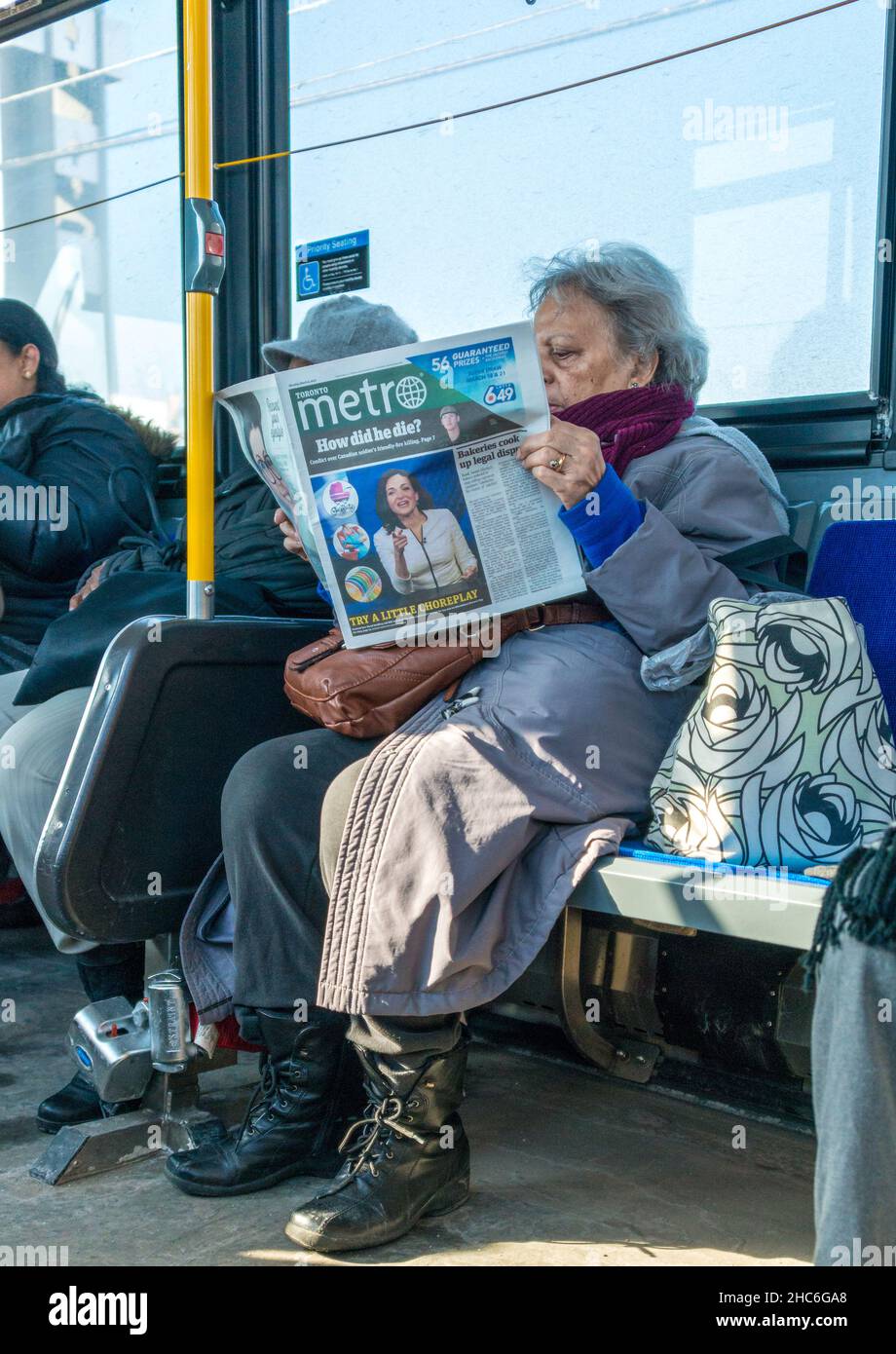 A Canadian woman reading a newspaper in a TTC bus about the ...