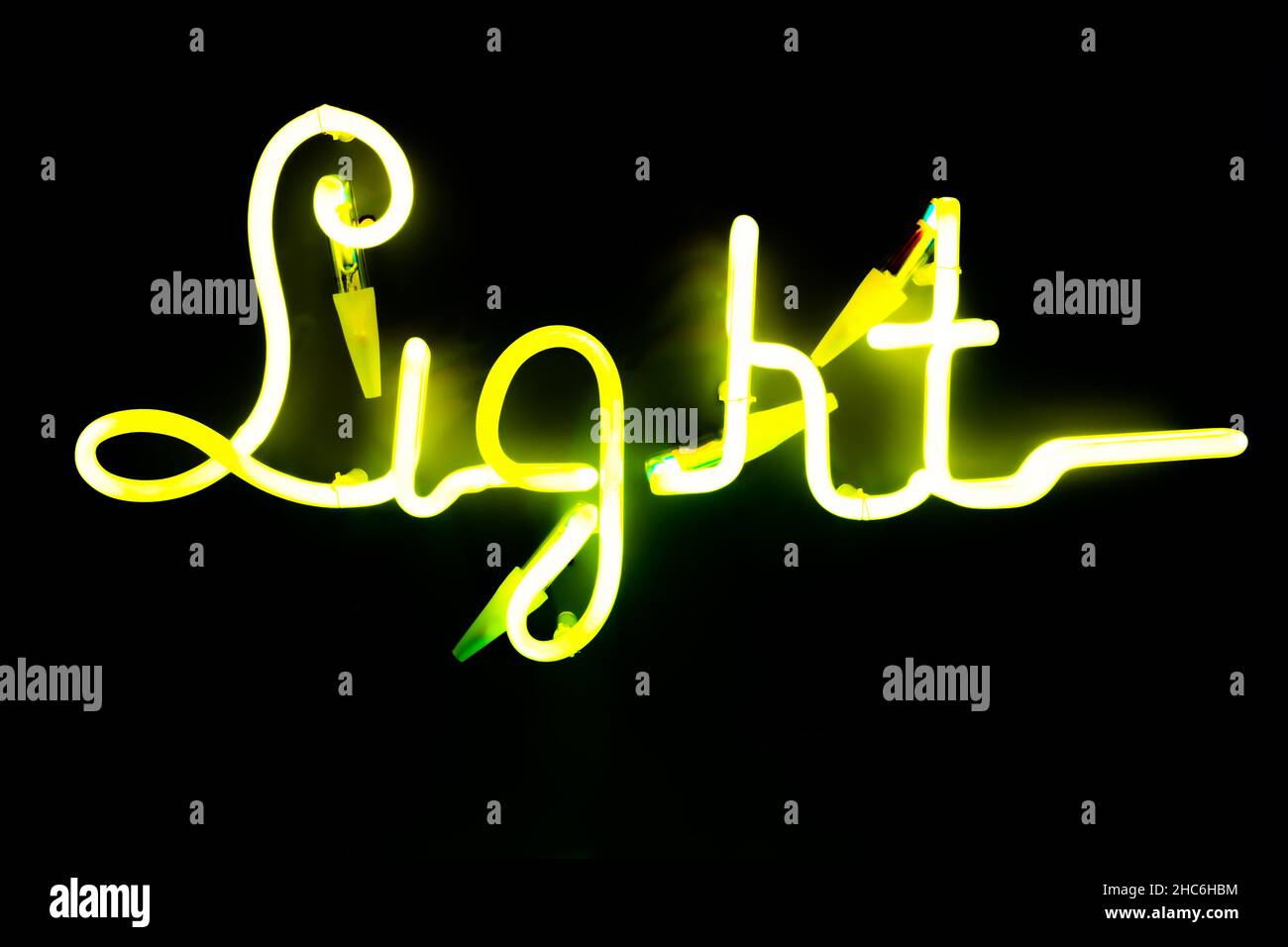 Illuminated letters written light on dark black background. Neon yellow ...