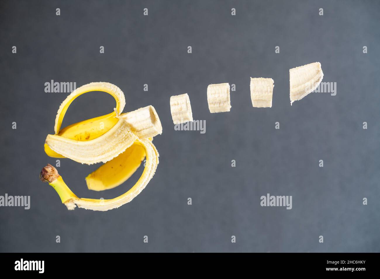Vertical sliced peeled banana isolated with a dark gray background ...