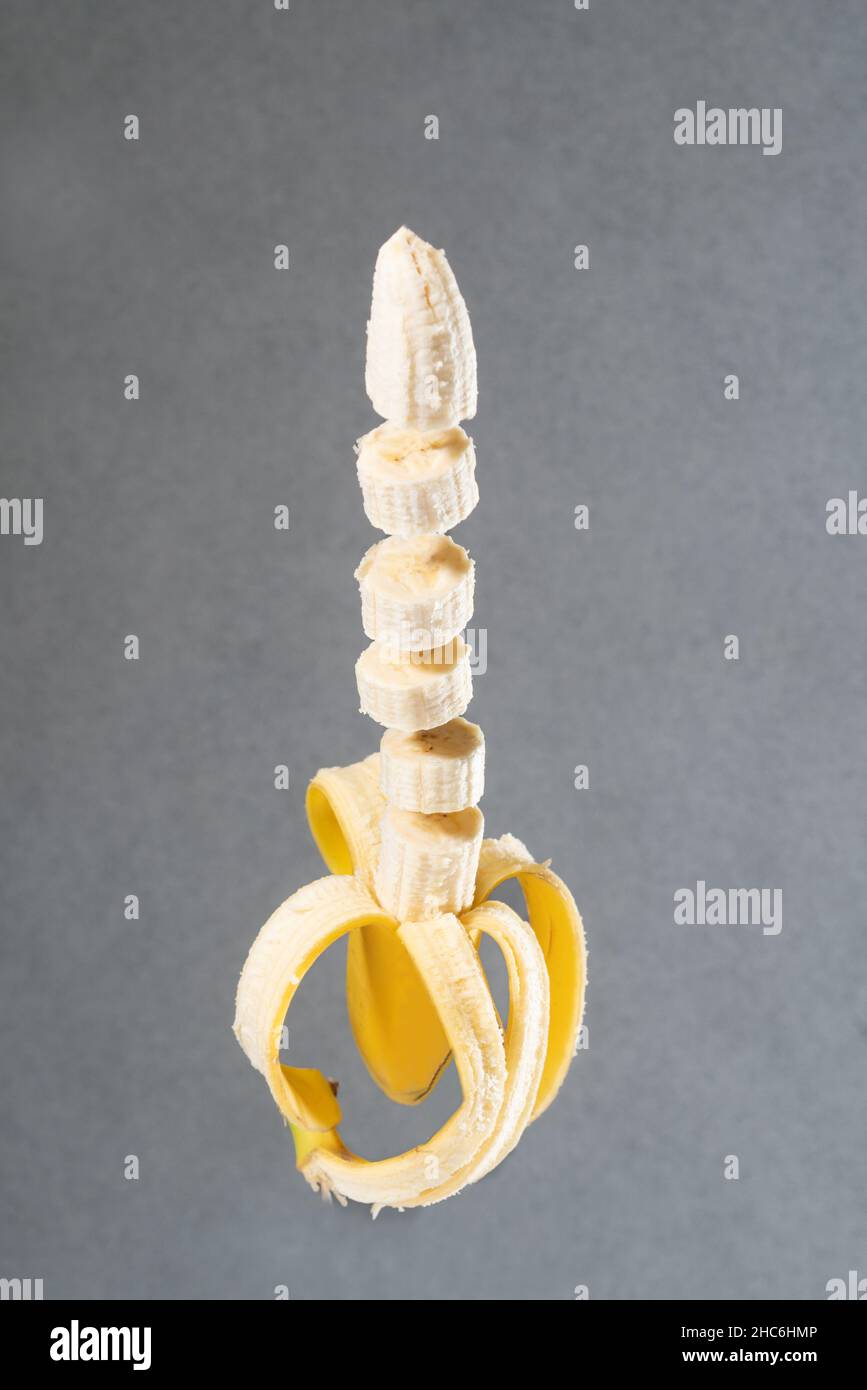 Vertical sliced peeled banana isolated with a dark gray background ...