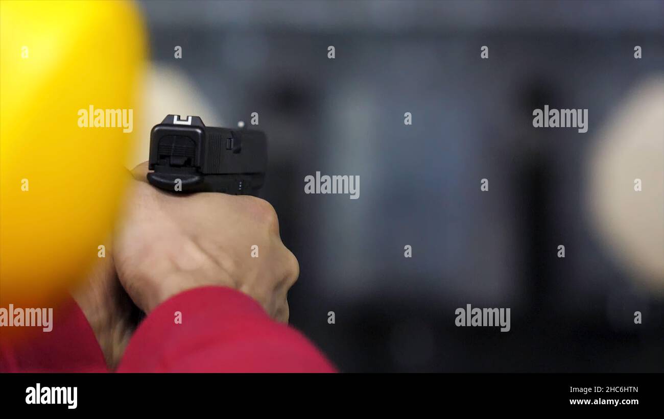Back view of man shoots a gun at shooting range close up. Man fires ...