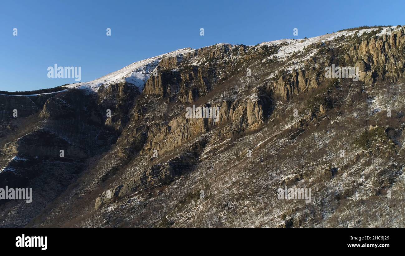 Aerial of snow covered hills with growing trees on the slopes on blue ...