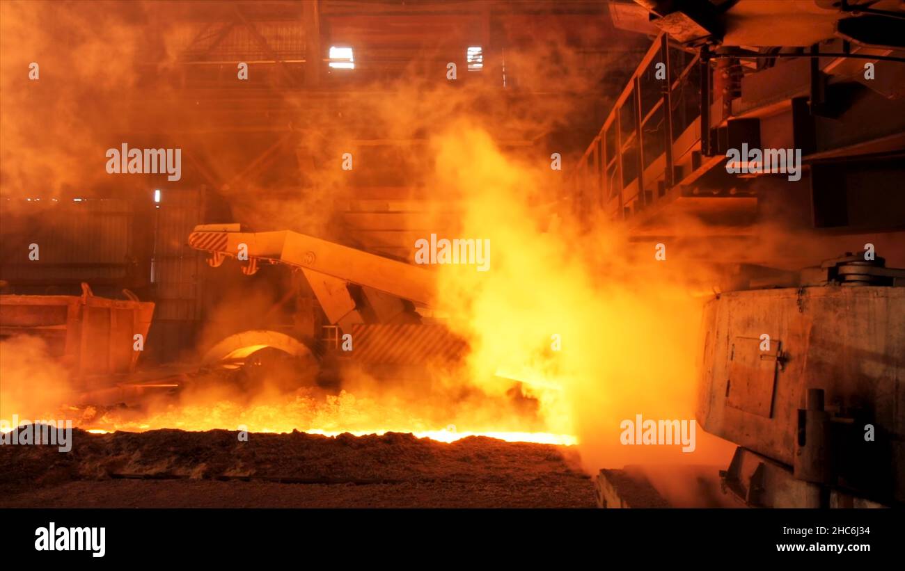 Hot steel being poured to the chute at the steel plant, heavy industry ...