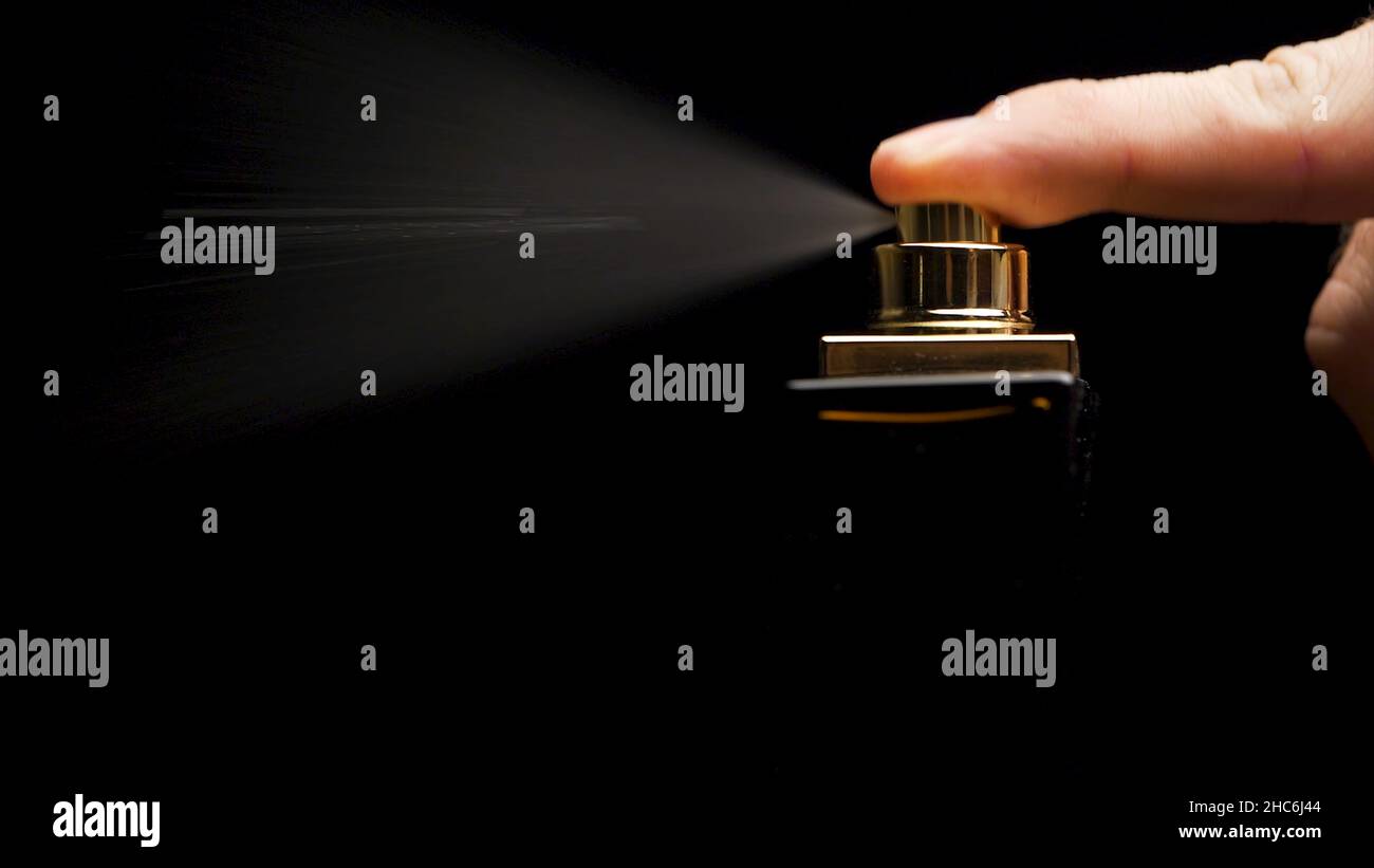 Perfume bottle with male finger on black background. Man applying ...