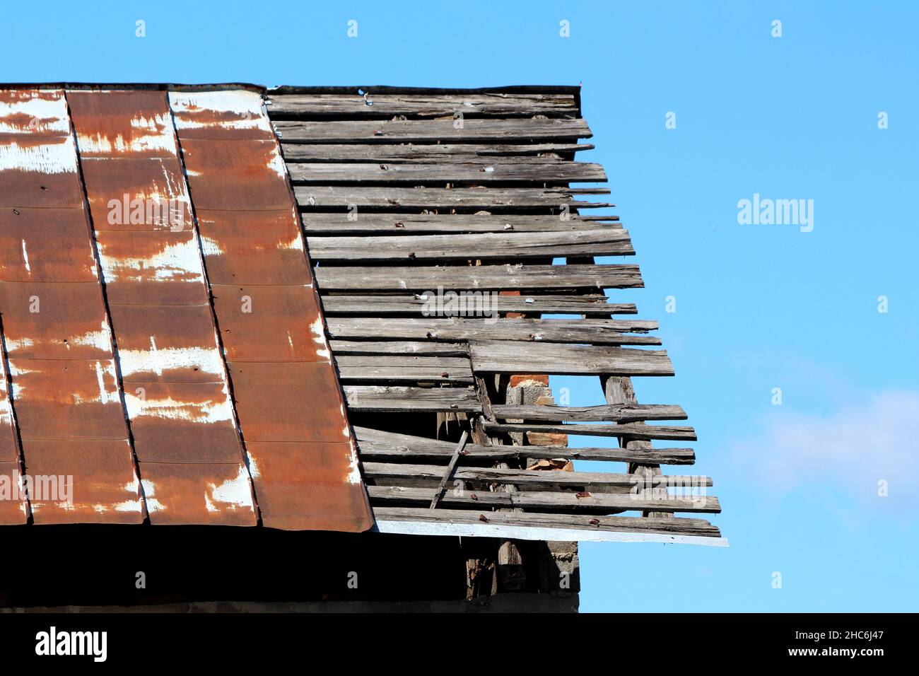 Destroyed abandoned family house roof with rusted metal roof tiles and ...