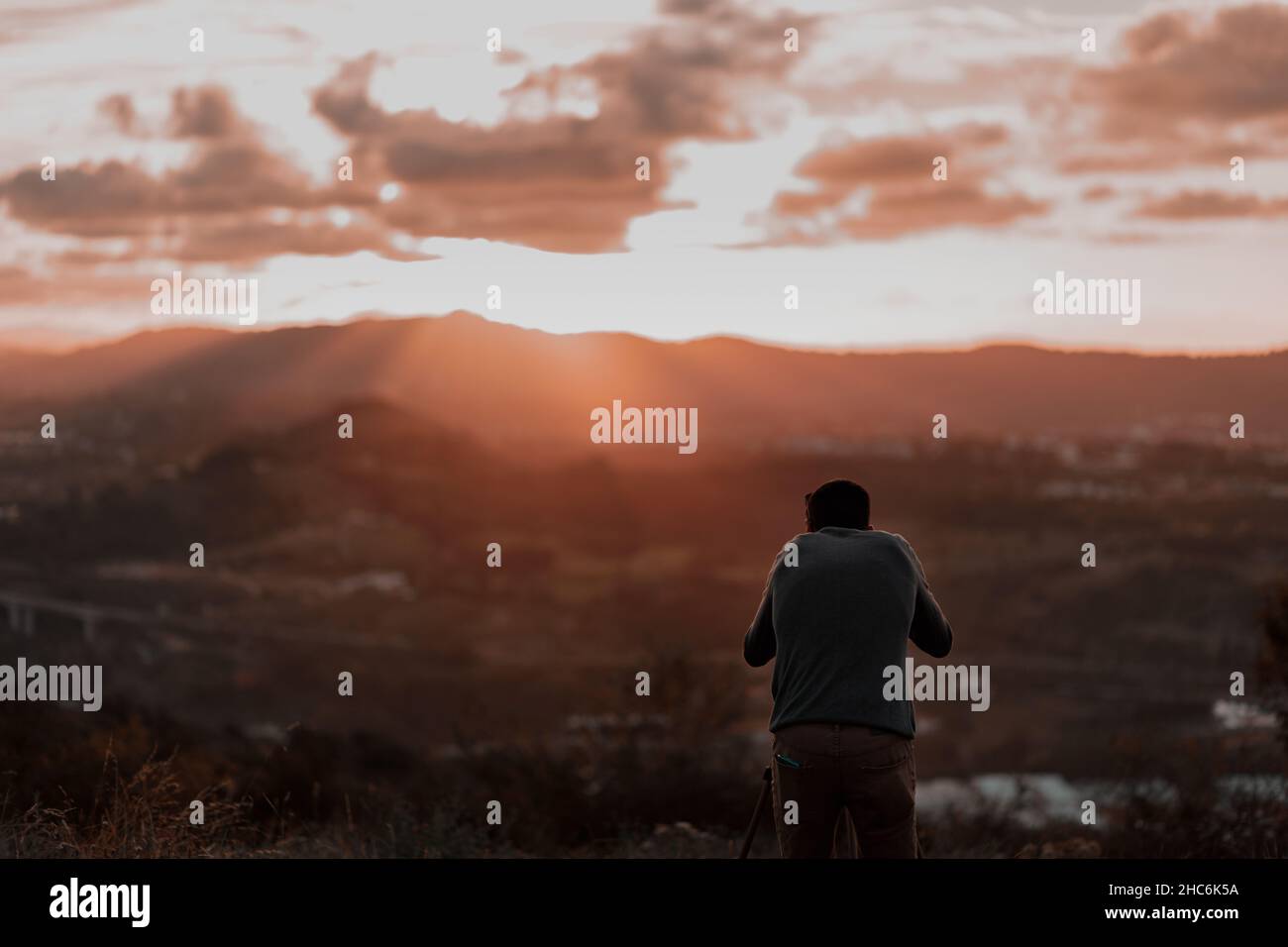 Back view of a male watching sunset over the mountains Stock Photo - Alamy