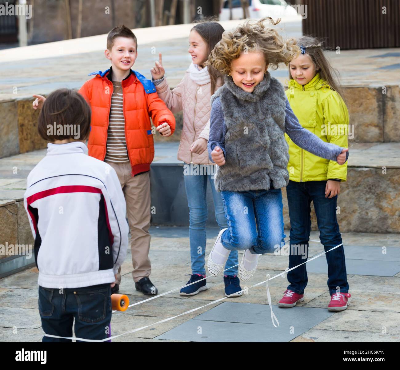 Kids playing with jump rope at street Stock Photo - Alamy