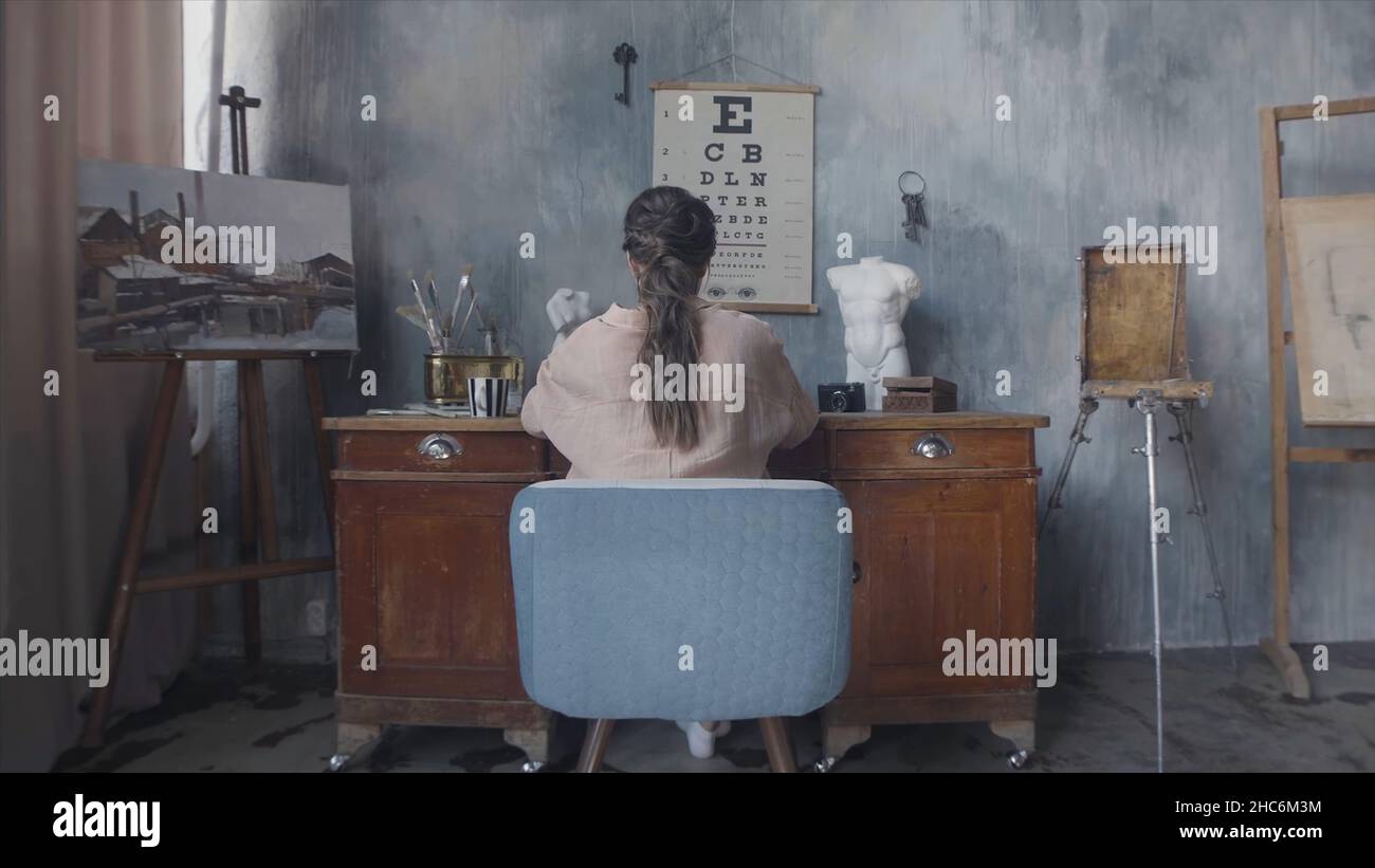 Businesswoman typing something on laptop and sitting at the desk, rear ...