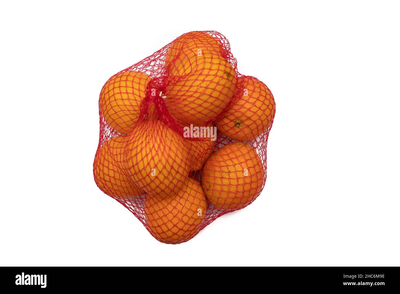 Closeup of fresh oranges in a plastic mesh sack, isolated on white ...