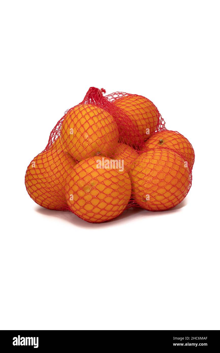 Closeup of fresh oranges in a plastic mesh sack, isolated on white ...