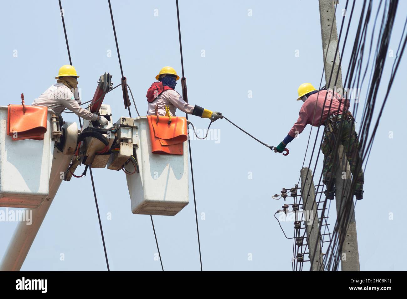 Electricians work together on the electric cable car and electric pole ...