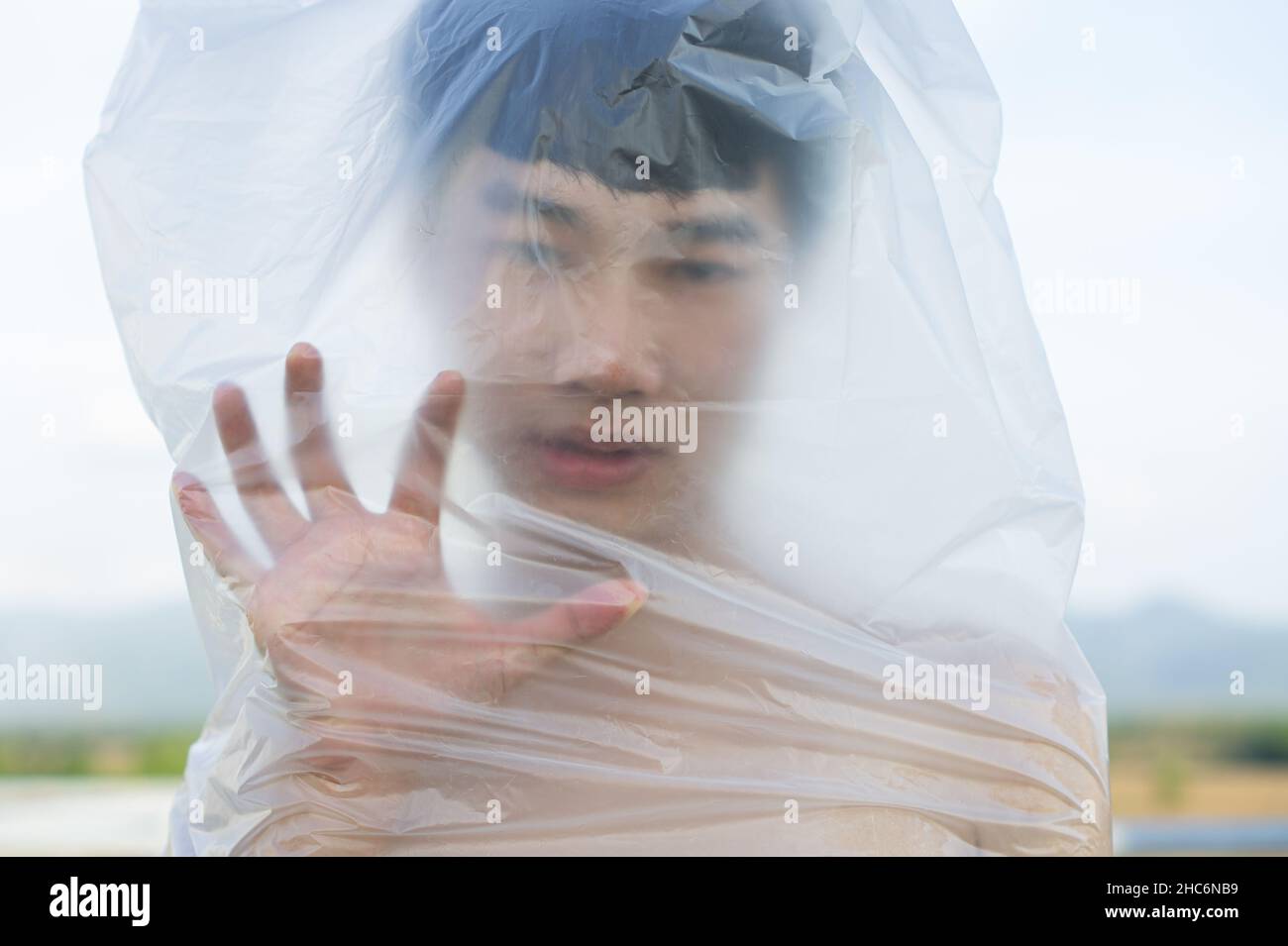 Asian gay man is wearing a plastic bag on his head that has suffocated ...