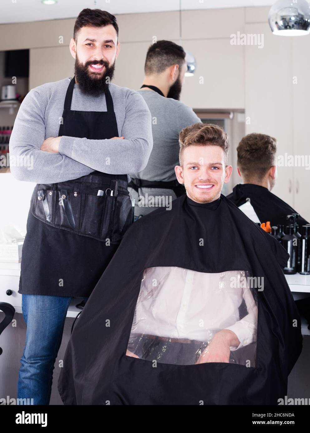 positive guy stylist demonstrating final haircut to client at ...