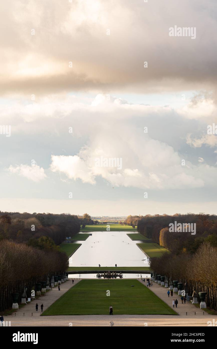 Canal surrounded by green trees at Versailles gardens against a cloudy ...
