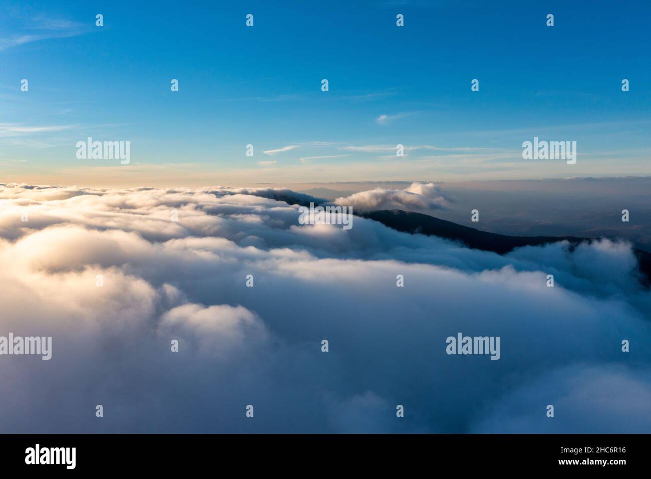 Blue sky above thick layer of white fluffy clouds at bright orange ...