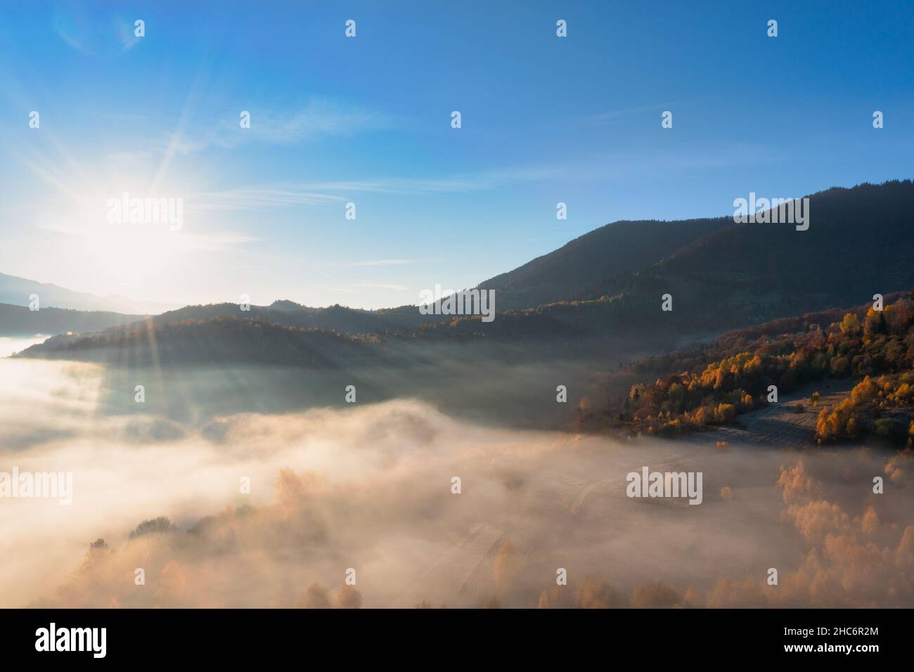 Thick layer of fog covering high mountains with terracotta and green ...