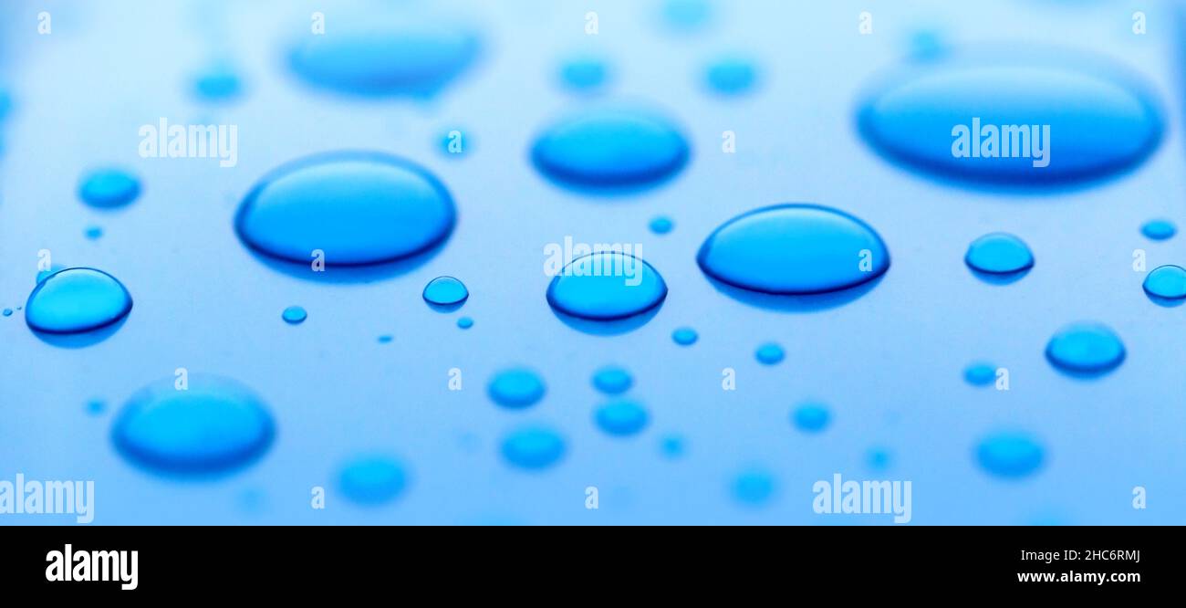 Large and small water droplets viewed from above on a blue background ...