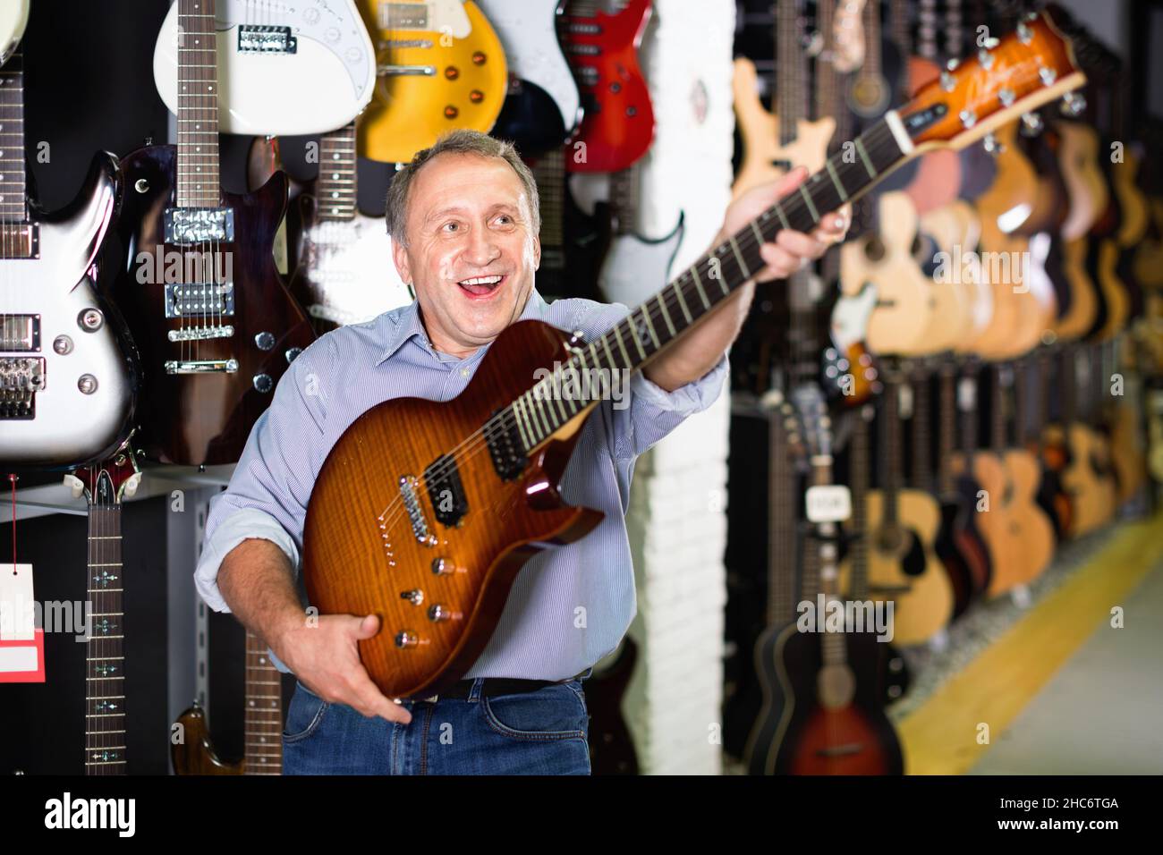 Adult guitarist is playing on electric guitar in music store Stock ...