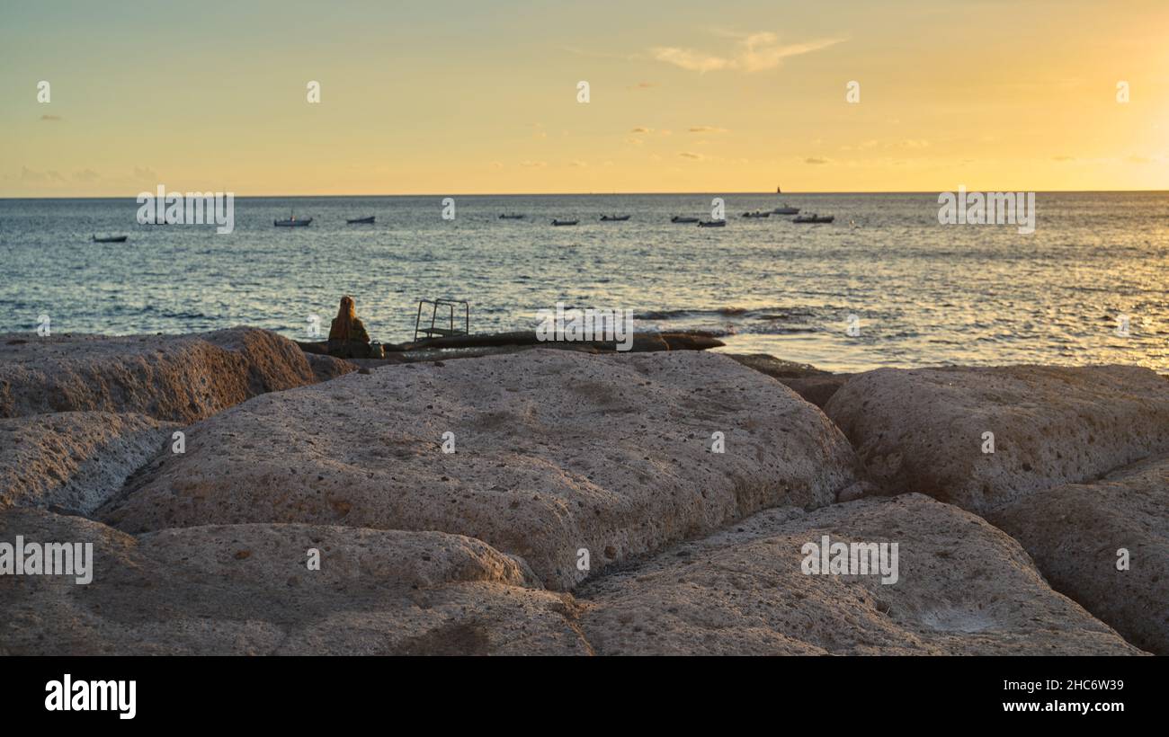 Woman watching boats splashing in the ocean at sunset Stock Photo - Alamy