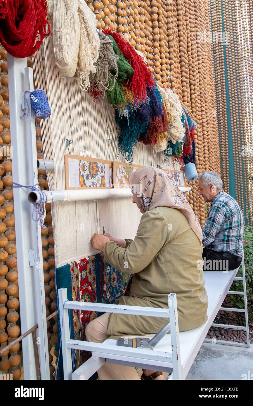 Old man and woman sitting and weaving a Persian carpet in Iran Pavilion ...