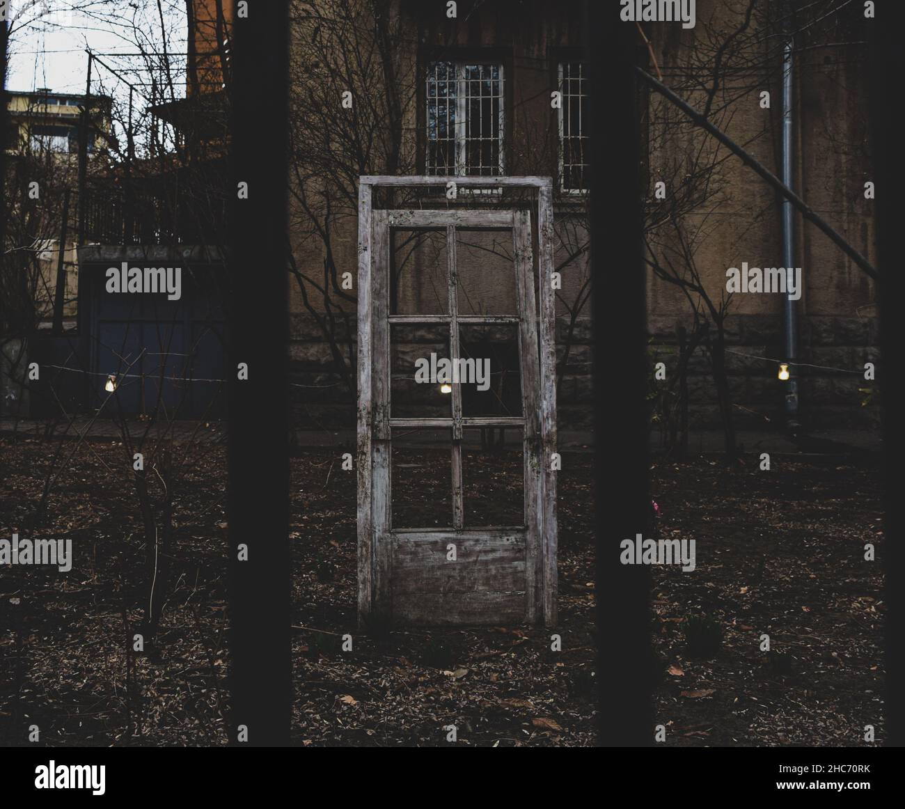 Moody scene from the gates of an old white door put on te fallen leaves ...