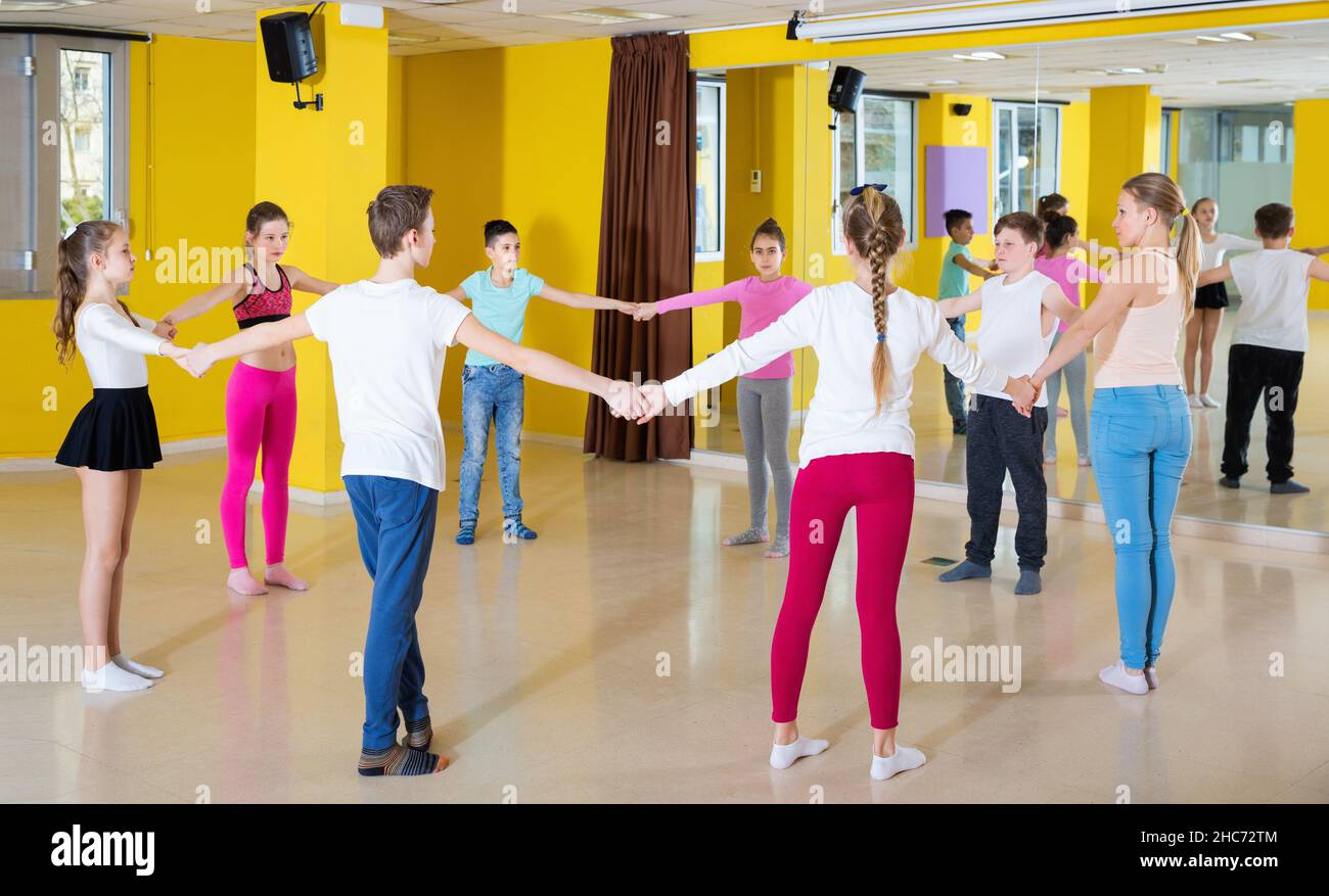 Teenage boys and girls practicing circle dance with female trainer in ...
