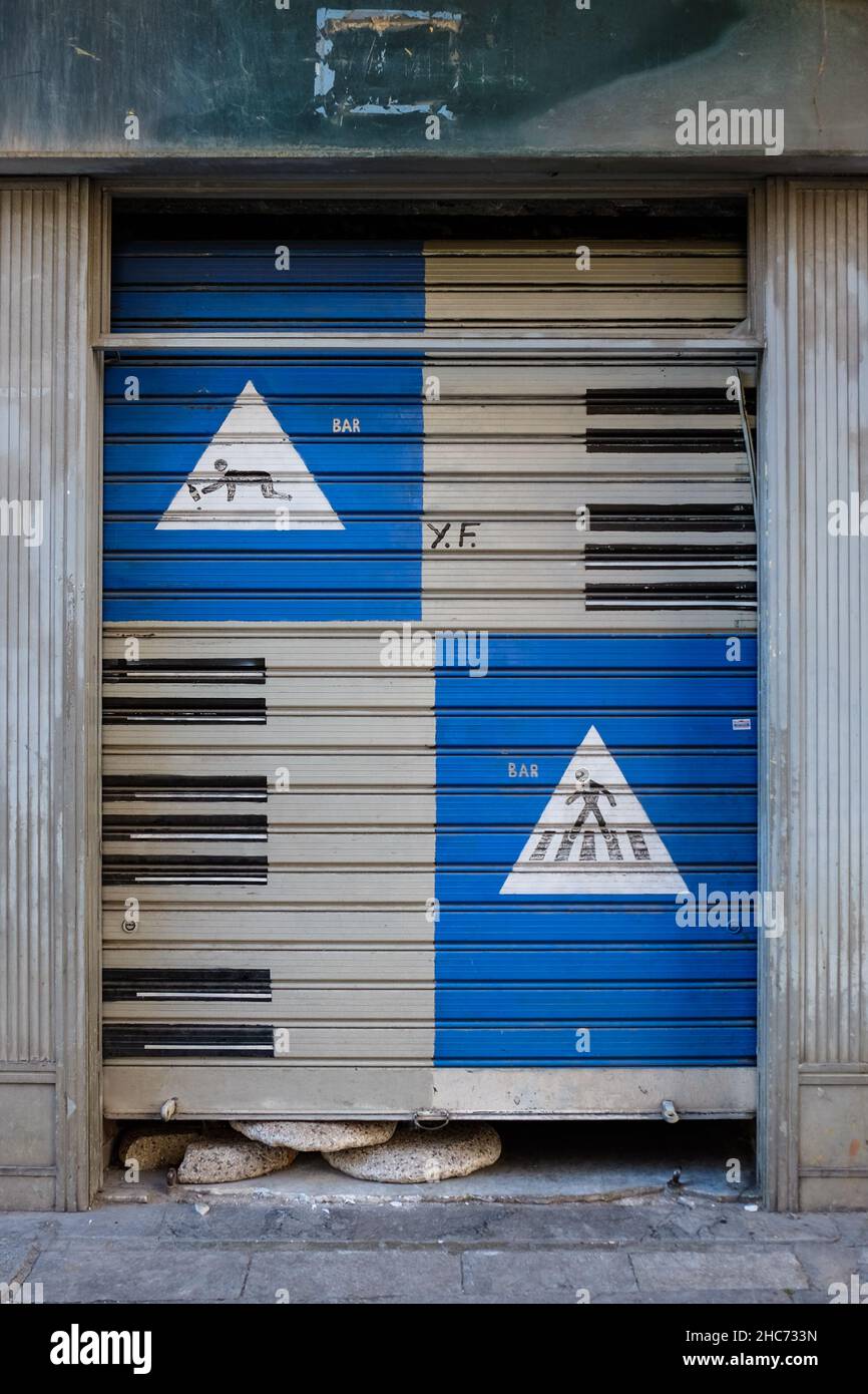 Vertical closeup of a painted shutter in the streets with blue road ...