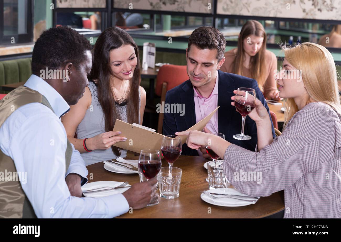 Happy people discussing restaurant menu Stock Photo - Alamy