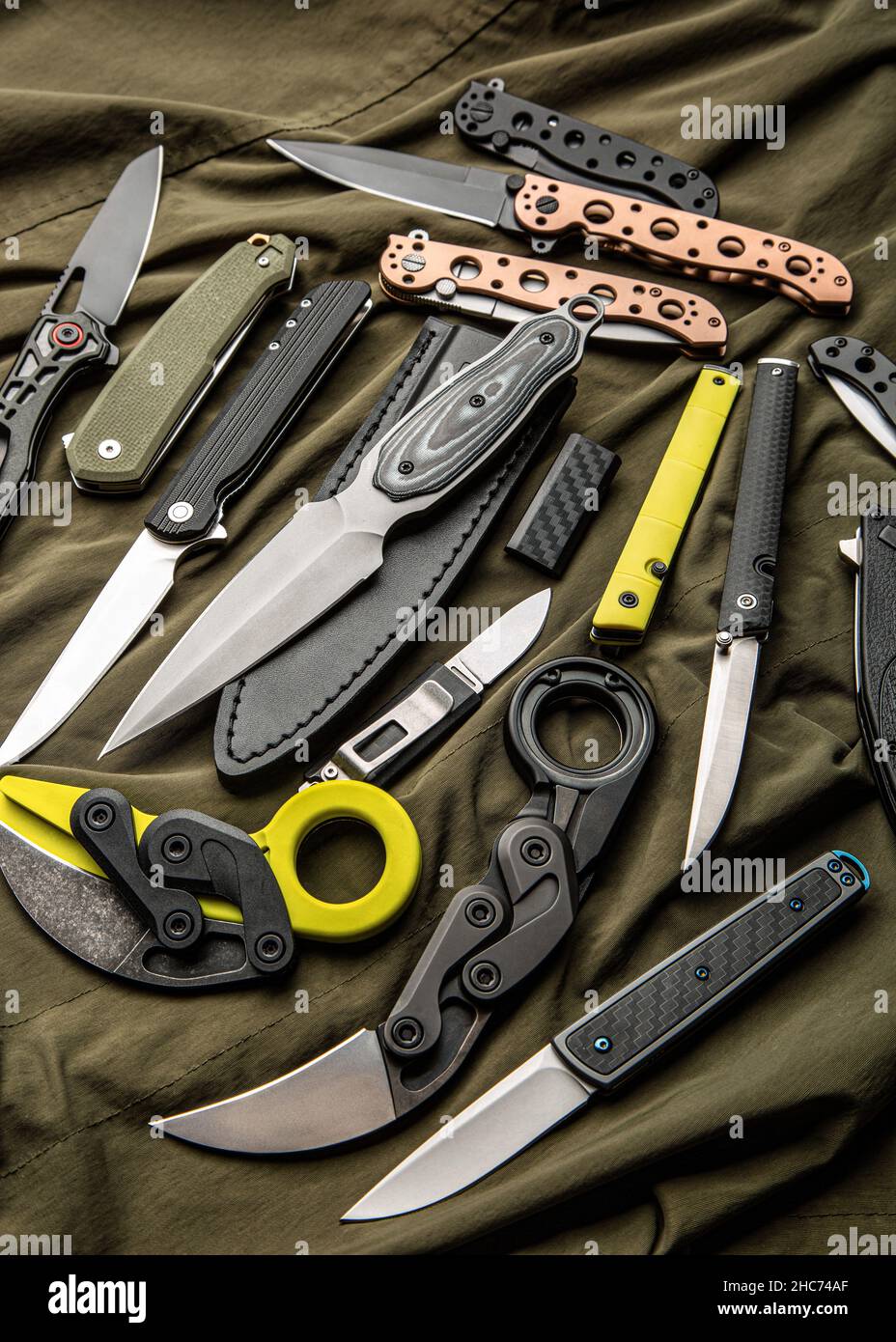 A variety of folding and pocket knives lie on khaki fabric. A versatile ...