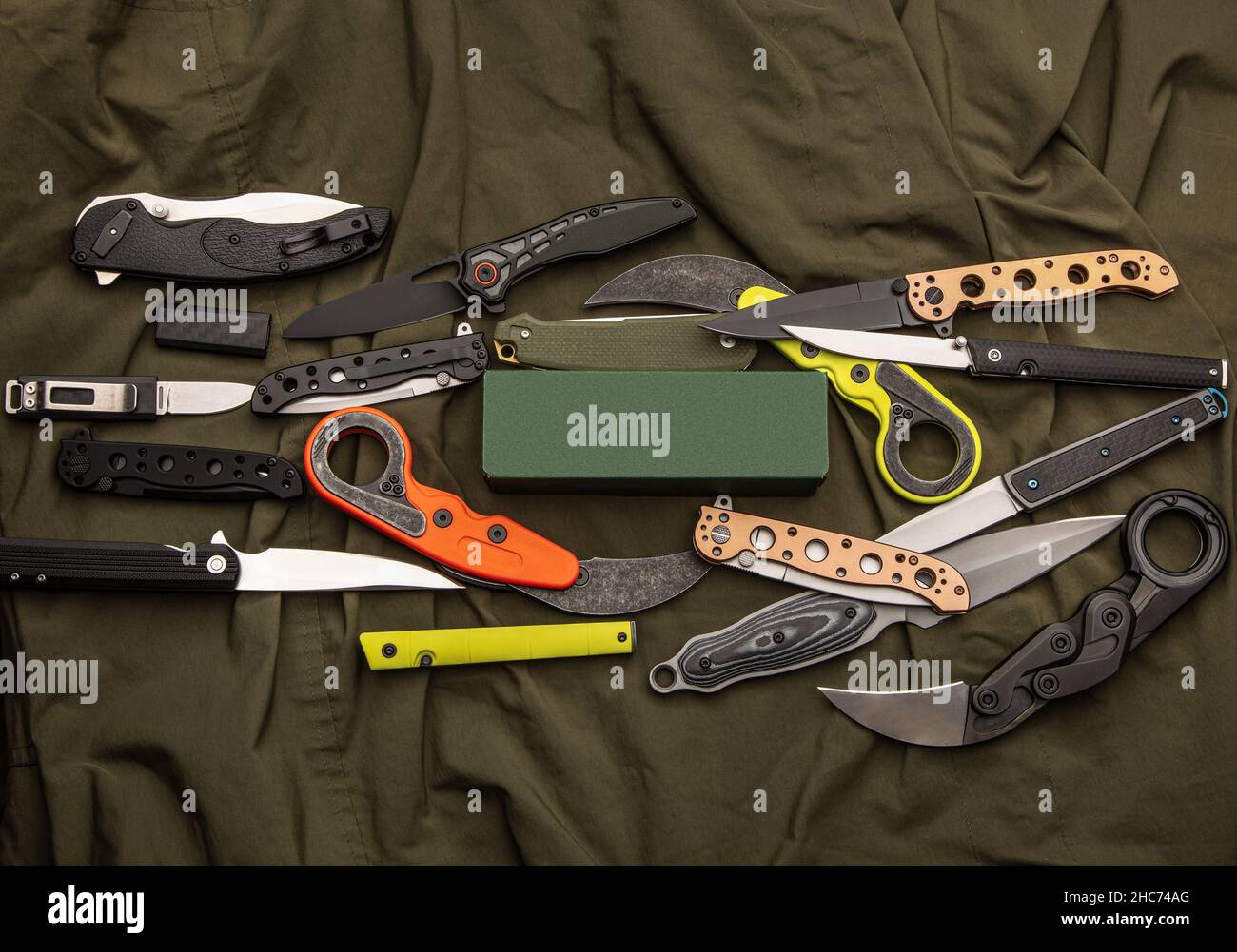 A variety of folding and pocket knives lie on khaki fabric. A versatile ...
