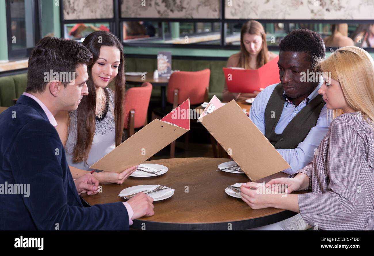 Happy people discussing restaurant menu Stock Photo - Alamy